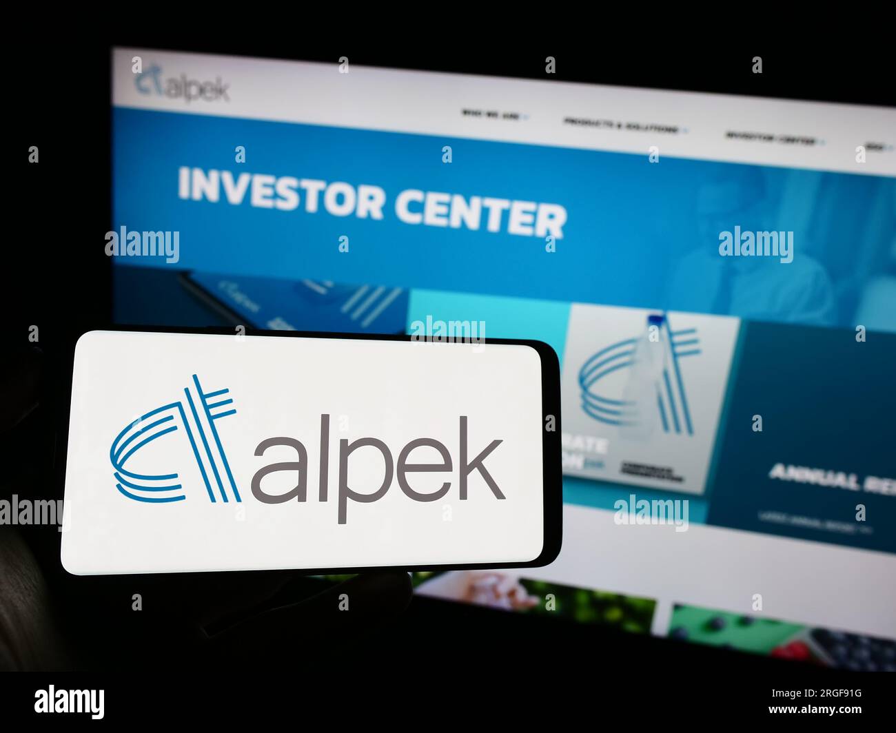 Person holding mobile phone with logo of Mexican chemical company Alpek S.A.B. de C.V. on screen ...