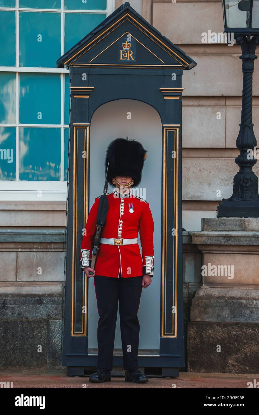 Royal soldier in red and black traditional uniform and bearskin hat in ...