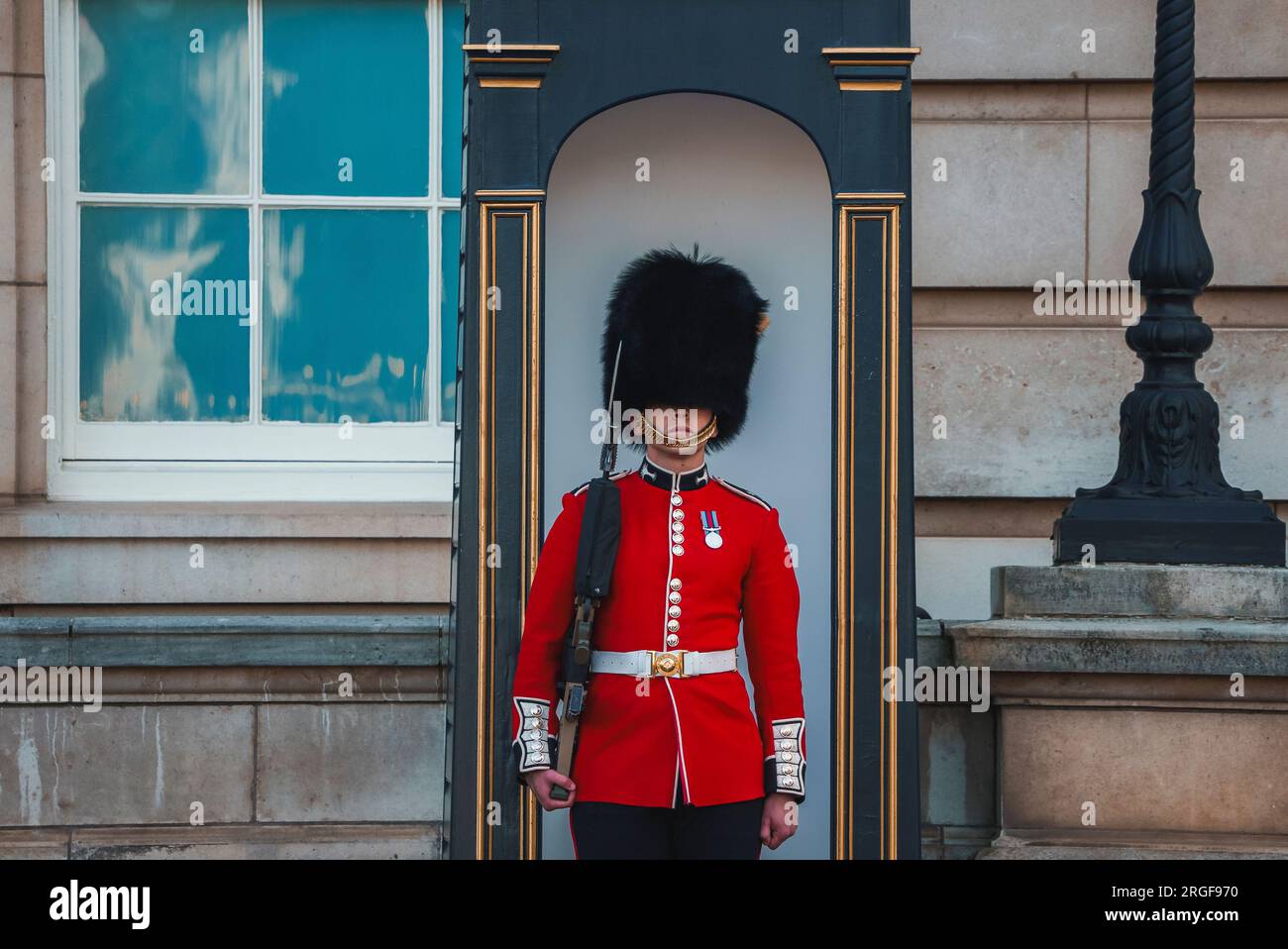 Royal soldier in red and black traditional uniform and bearskin hat in ...