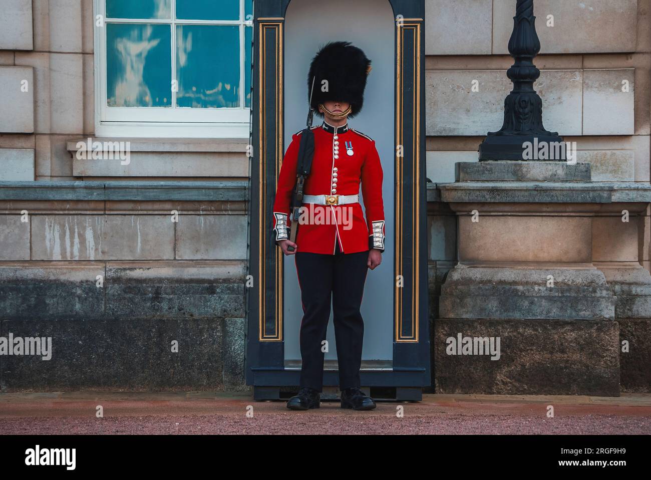 Guard in red and black traditional uniform and bearskin hat in front of ...