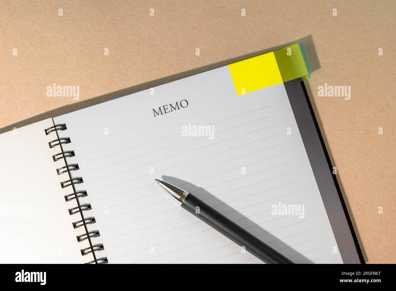 Notebook with yellow page marker note and pen on table. Blank pages for ...