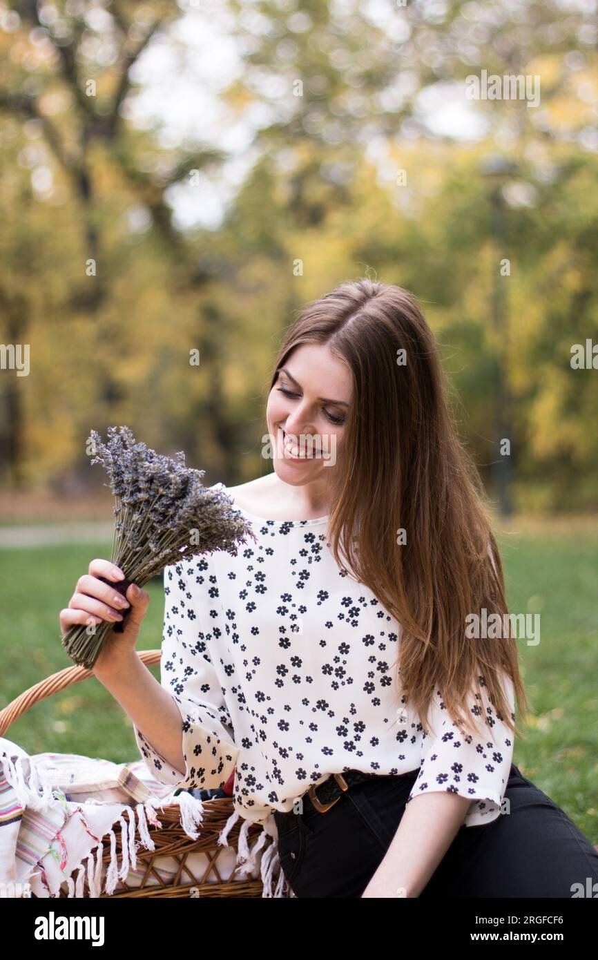 Young ginger haired woman enjoying the calming smell of a bouquet of lavender in the park Stock ...