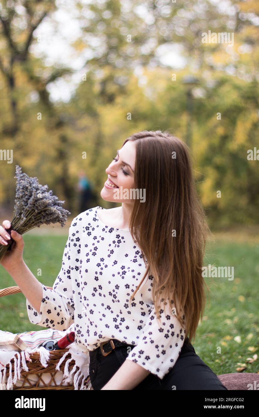 Young ginger haired woman enjoying the calming smell of a bouquet of lavender in the park Stock ...