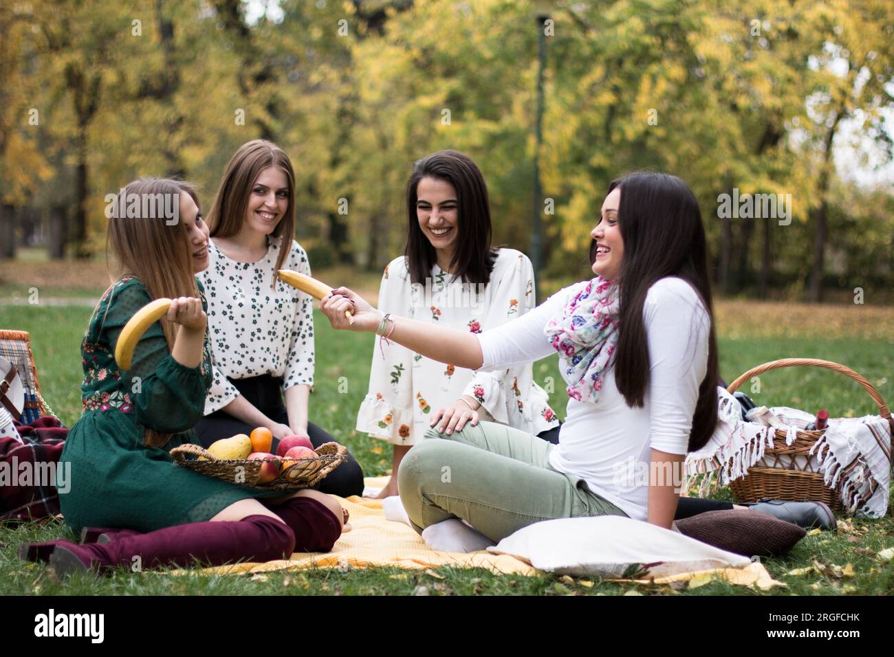 Group of four women on a fun fall picnic in the park, having a good ...