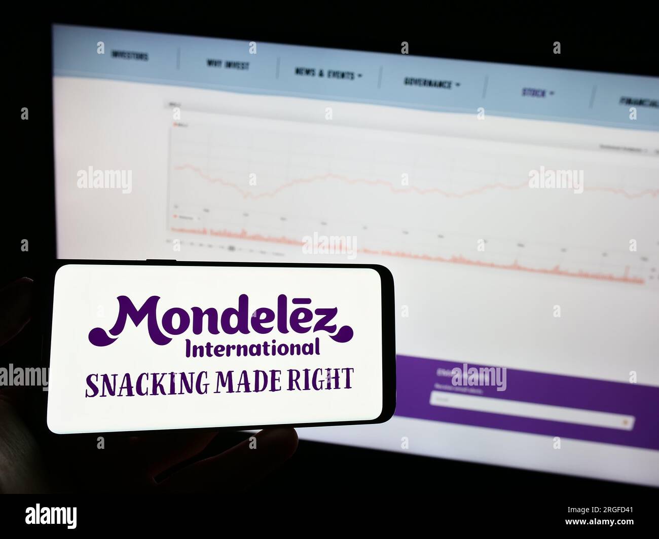 Person holding mobile phone with logo of American food company Mondelez ...