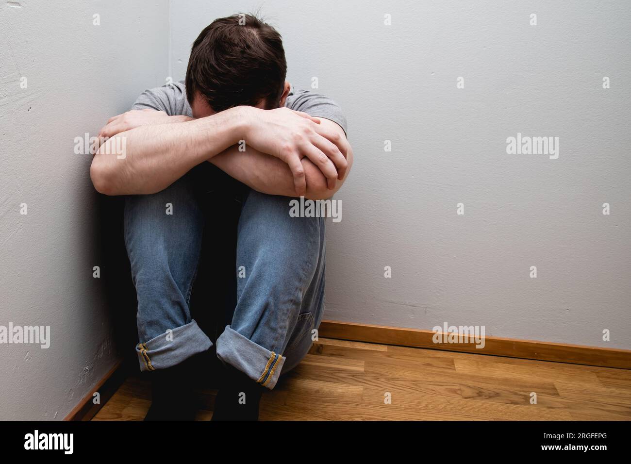 depressed man sitting in a corner of a room Stock Photo - Alamy