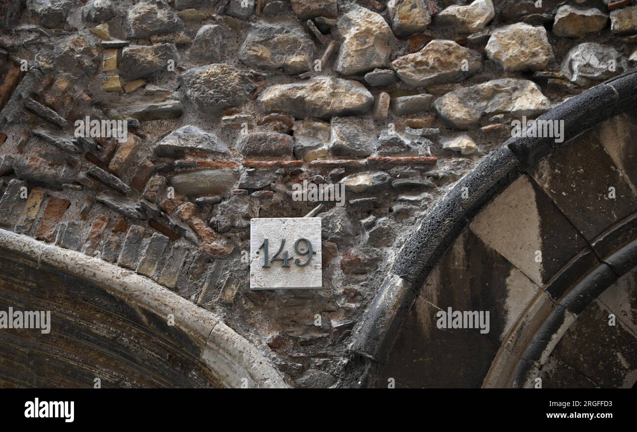 Antique handcrafted stone wall with a street number sign in Taormina ...