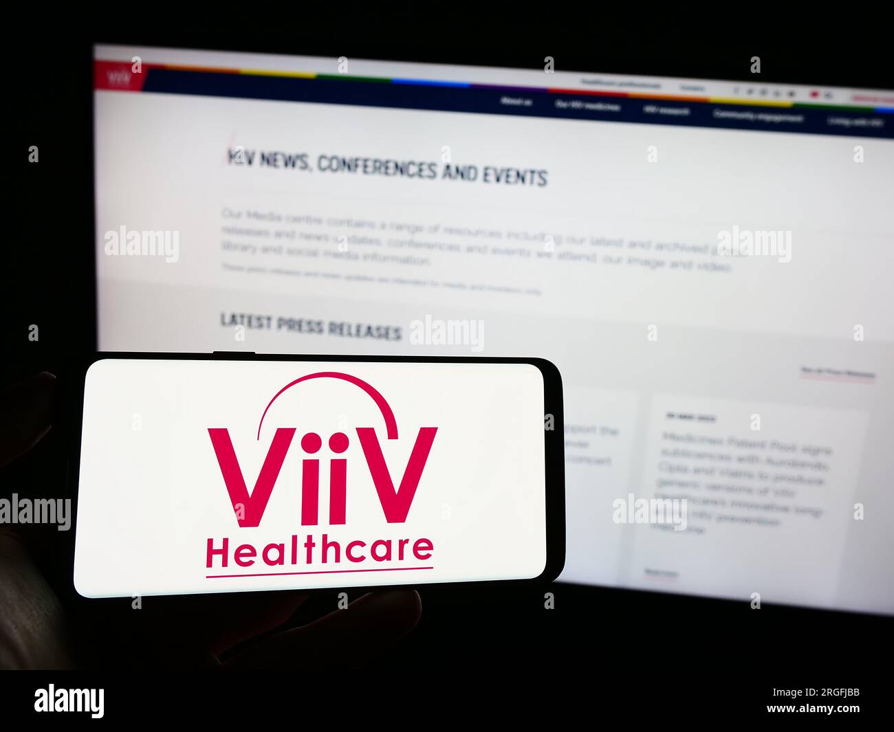 Person holding cellphone with logo of British pharmaceutical company ViiV Healthcare on screen ...