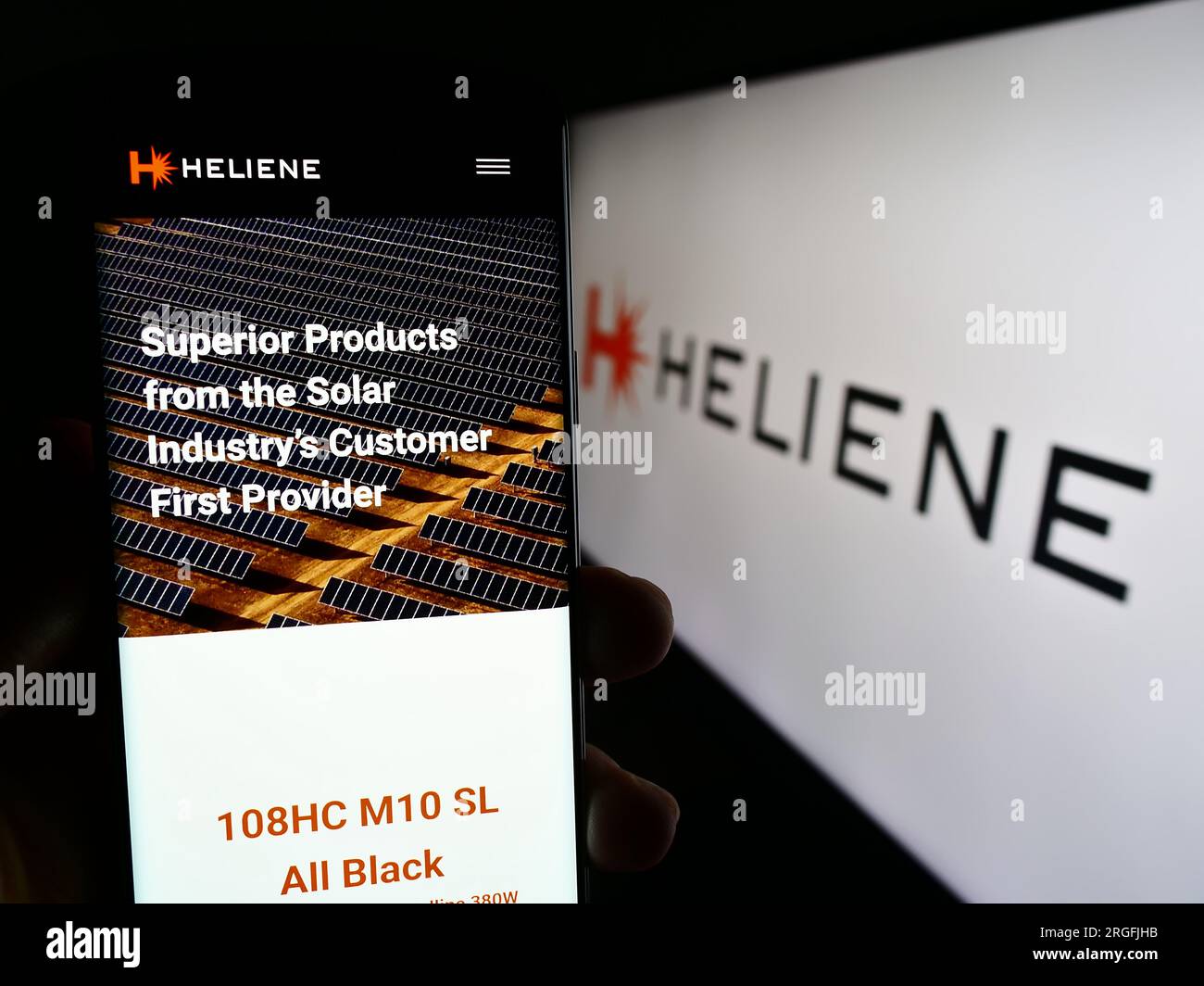 Person holding mobile phone with web page of US solar panels company ...