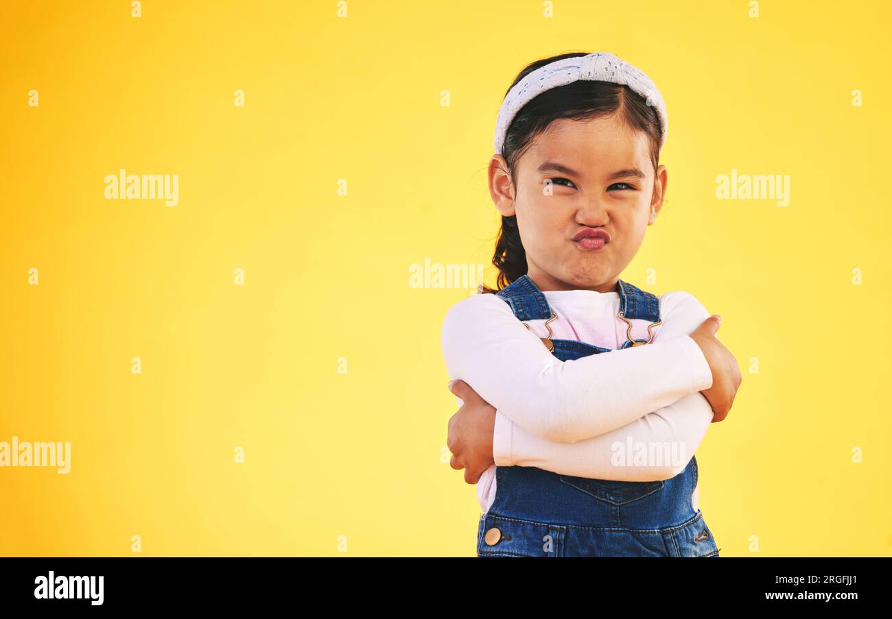 Arms crossed, portrait and angry girl child in studio with bad ...