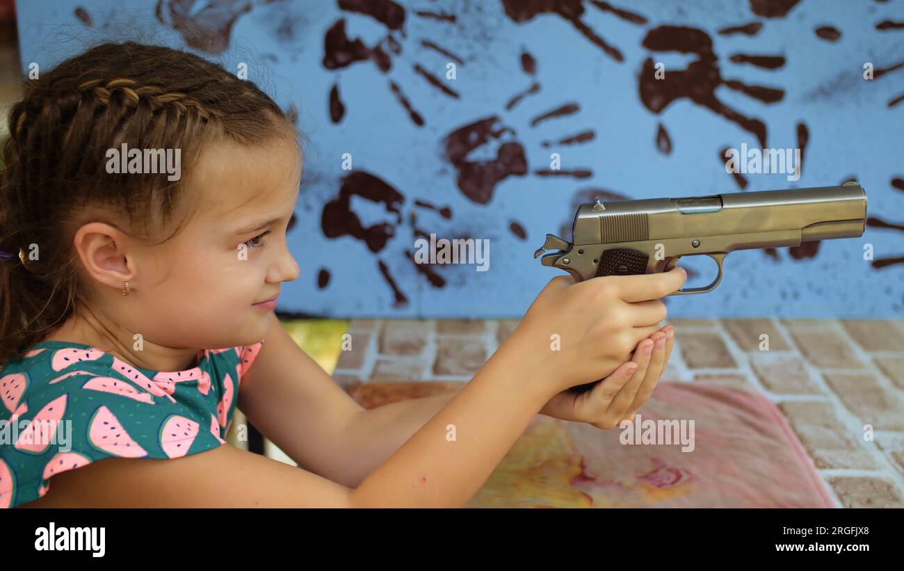 Little girl shoots at shooting range with gun. Outdoors entertainment ...