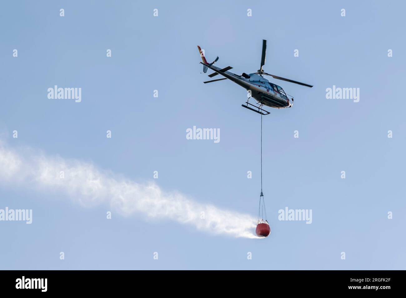 Helicopter engaged in a fire-fighting operation with the use of a large ...