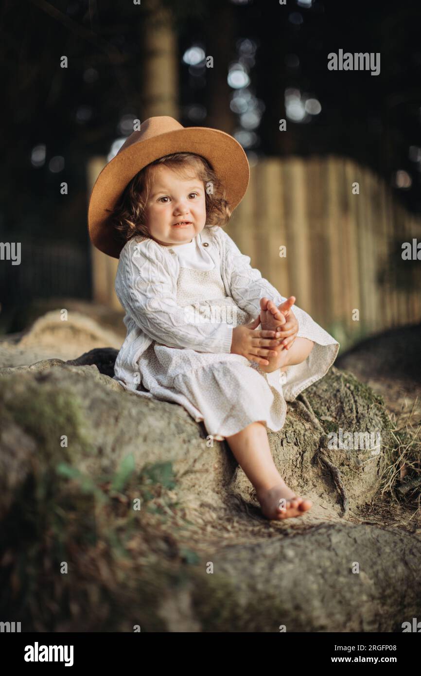 Little girl wearing hat, sitting bootless in the countryside Stock ...