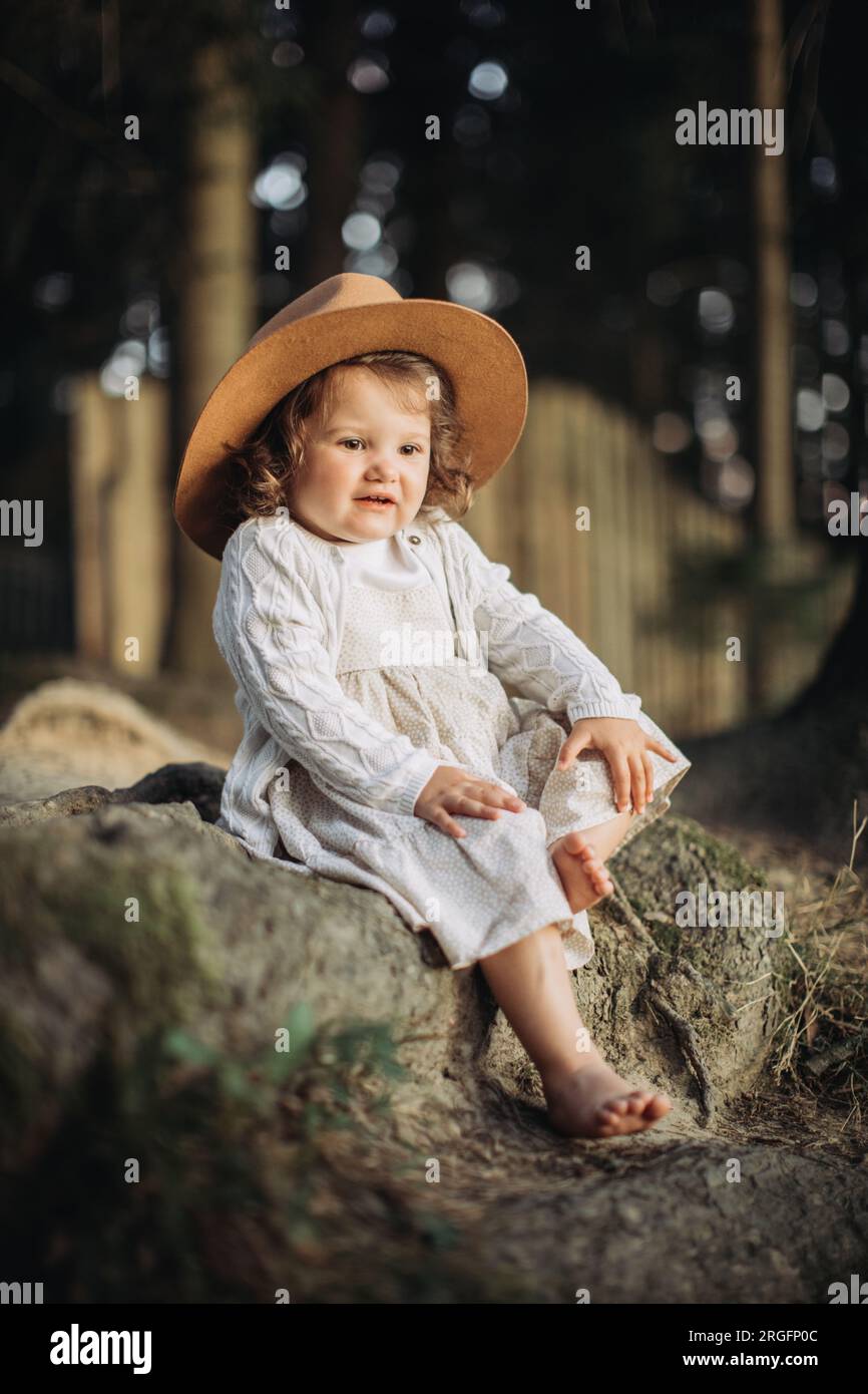 Little girl wearing hat, sitting bootless in the countryside Stock ...