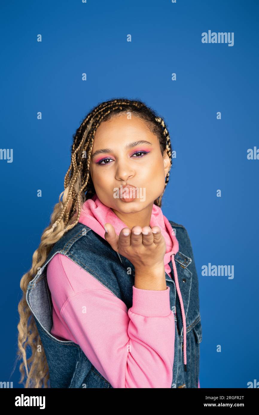 beautiful african american woman sending air kiss on blue background ...