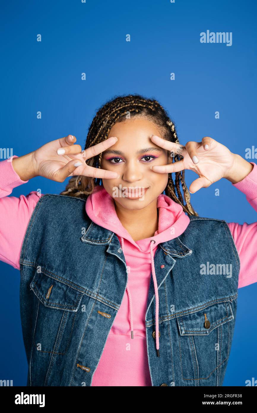 attractive and happy african american woman on blue background, denim ...
