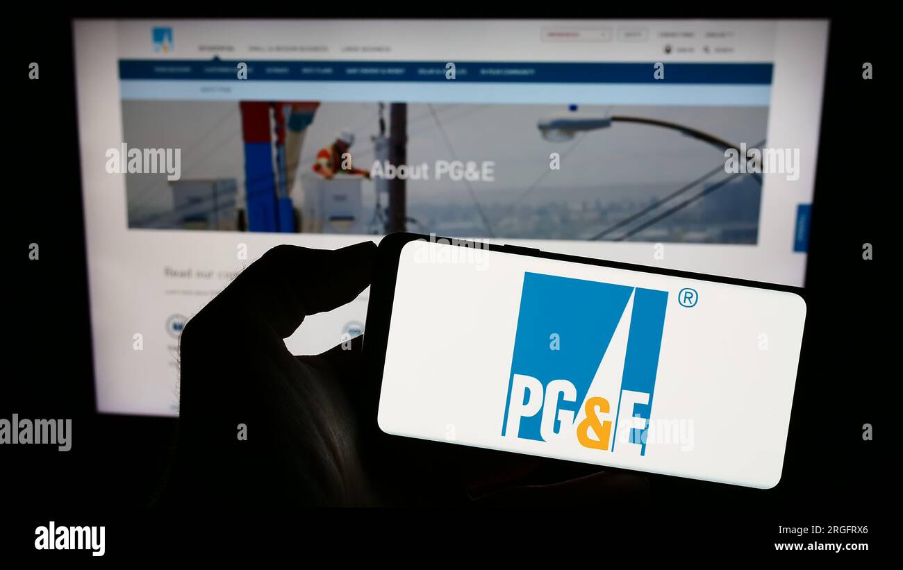 Person holding smartphone with logo of utility Pacific Gas and Electric ...