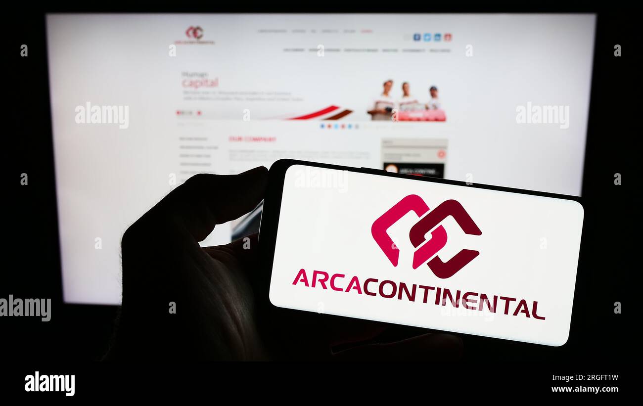Person holding mobile phone with logo of company Arca Continental SAB ...