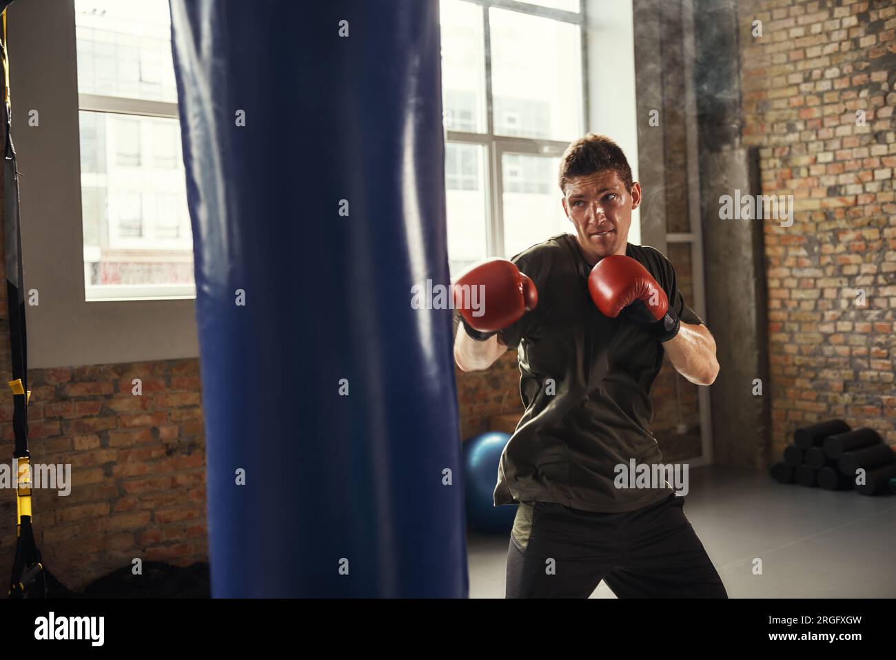 Best fighter. Young and strong man boxing in red gloves in a loft style ...