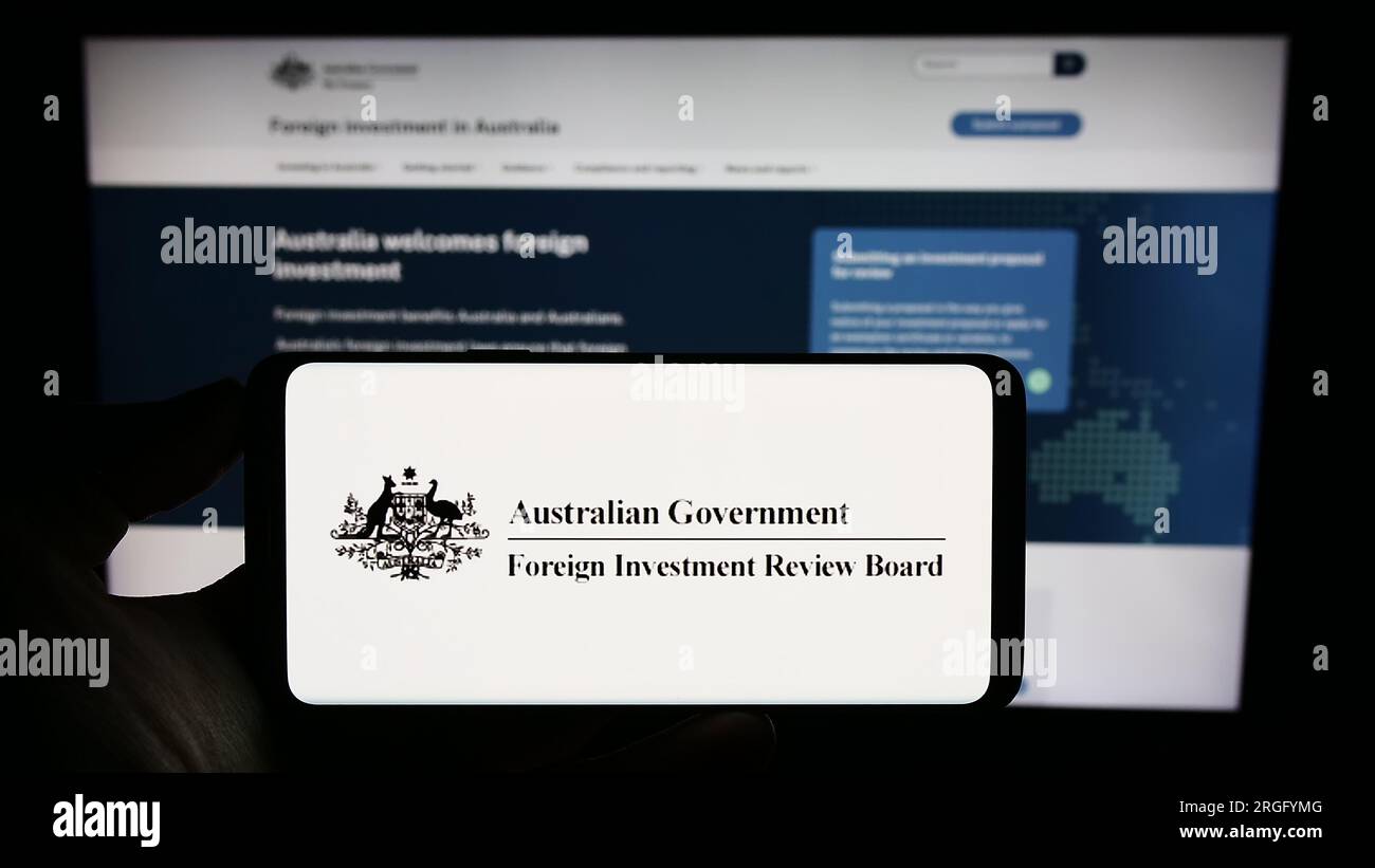 Person holding cellphone with logo of Australian Foreign Investment ...