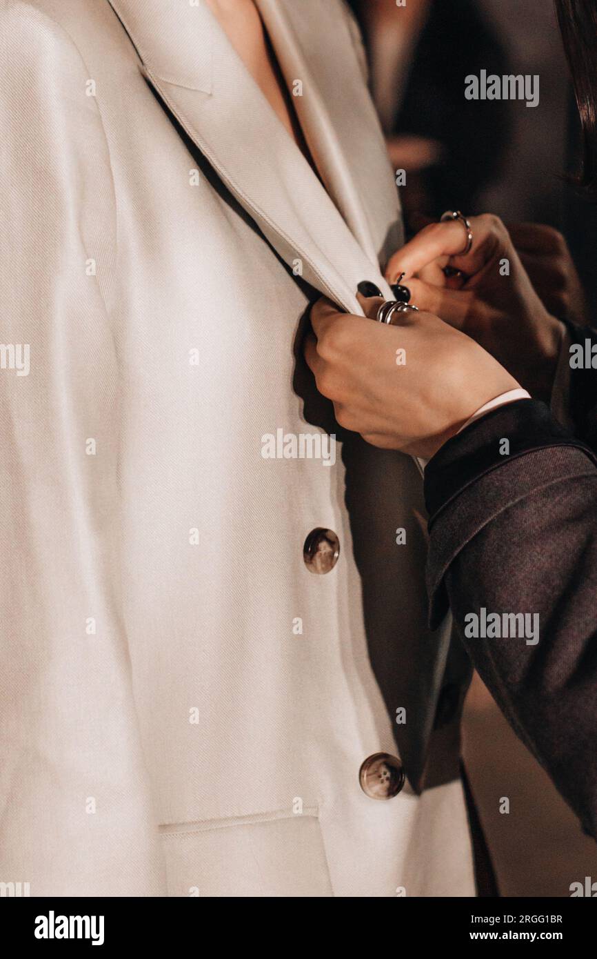 Female hands preparing fashion model dressed in white classy jacket ...