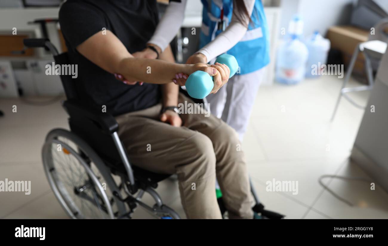 Paralyzed man sit in wheelchair and hold blue dumbbell on his ...
