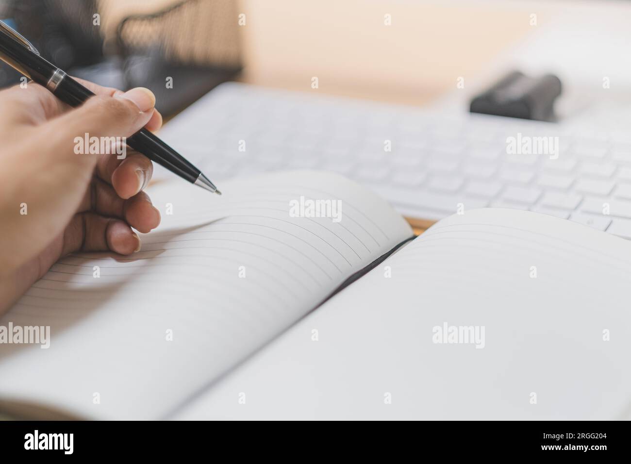 Close-up hand holding pen and write on white book Stock Photo - Alamy
