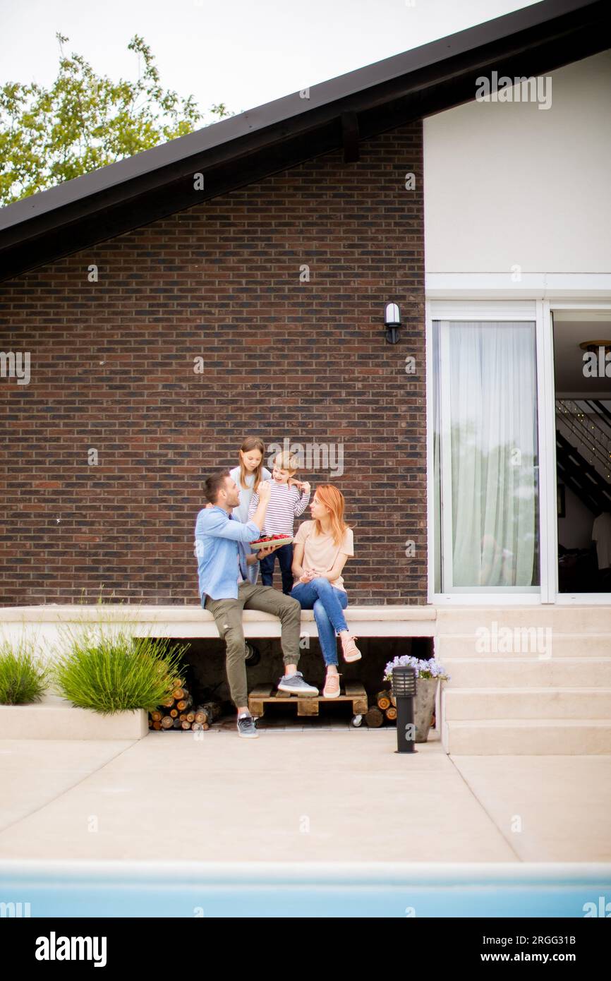 Family with a mother, father, son and daughter sitting outside on a ...