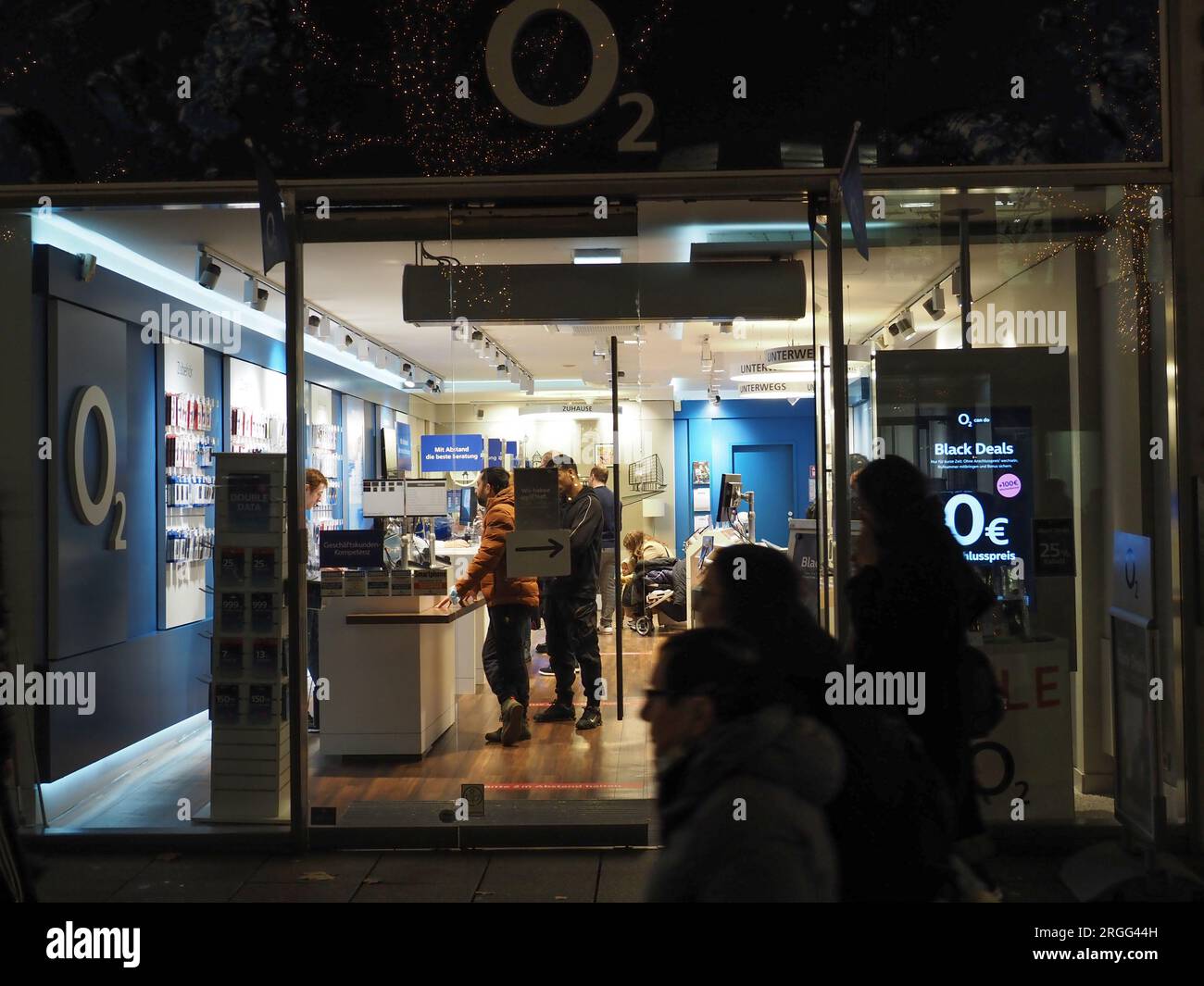 People in front of a O2 store at night. Telefonica operates under the ...