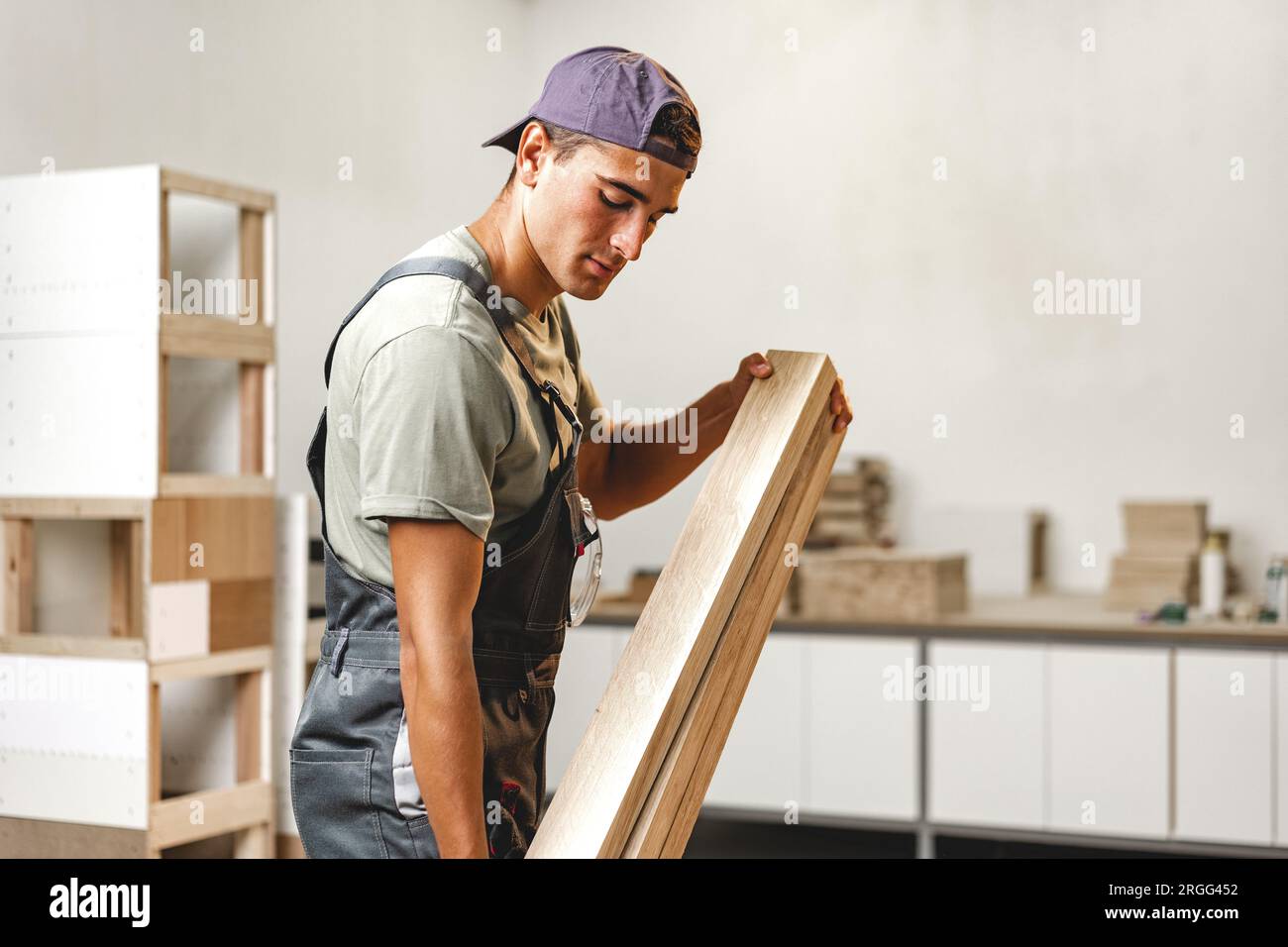 Young carpenter man looking and choosing wood plank at workshop in ...