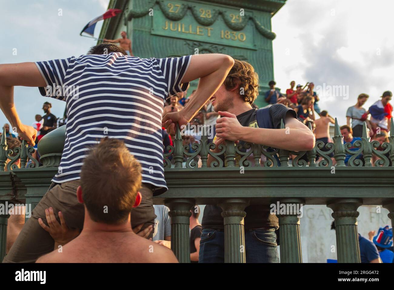 Paris, France, 2018. Two friends are helping a man get over the railing ...