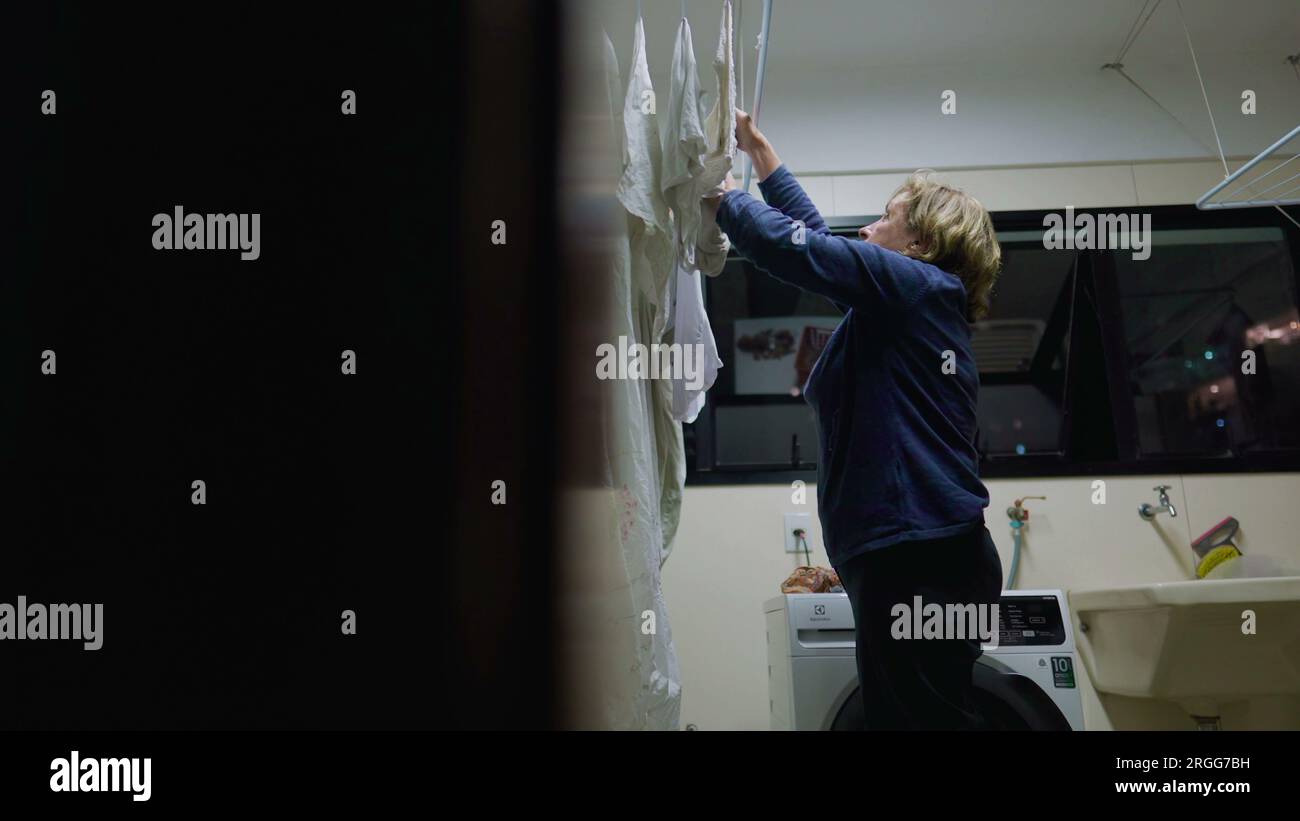 Senior woman tending to laundry on drying rack, a glimpse into daily ...