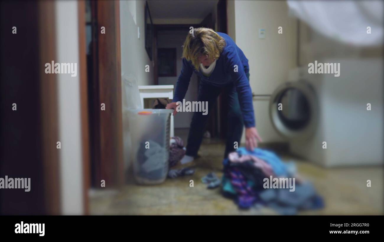 One candid senior woman doing laundry chores at home. Domestic scene of ...
