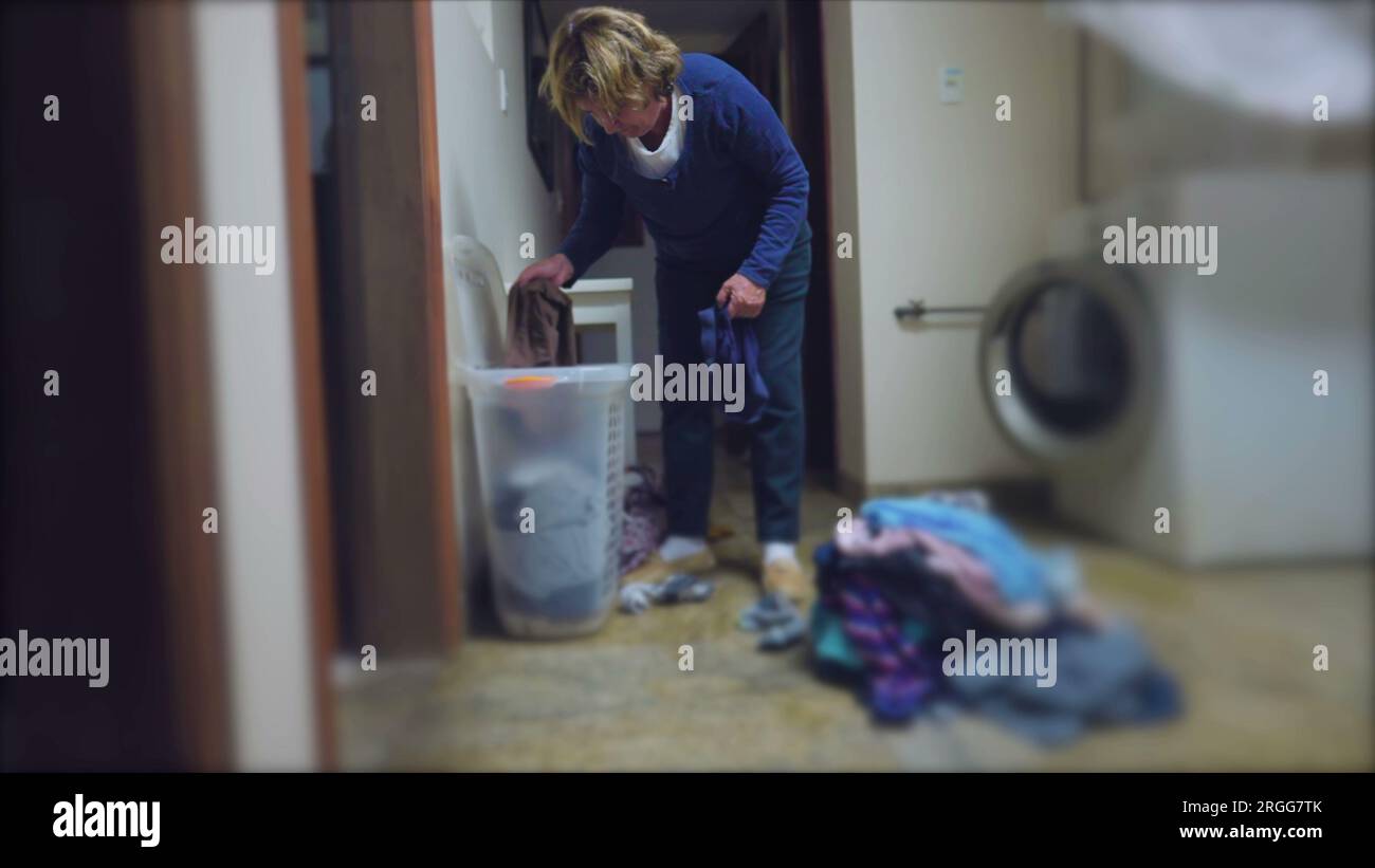 One candid senior woman doing laundry chores at home. Domestic scene of ...