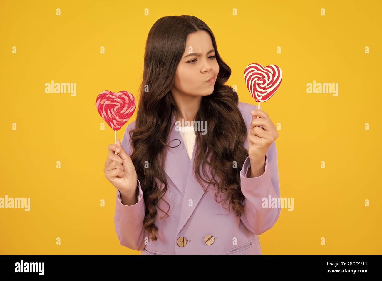 Funny face. Teen girl hold lollipop caramel on yellow background, candy ...
