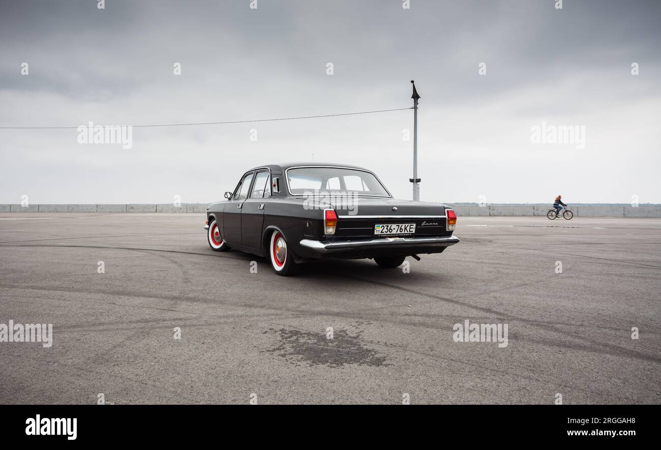 black classic GAZ Volga sedan from 1970s parked on big empty asphalt ...