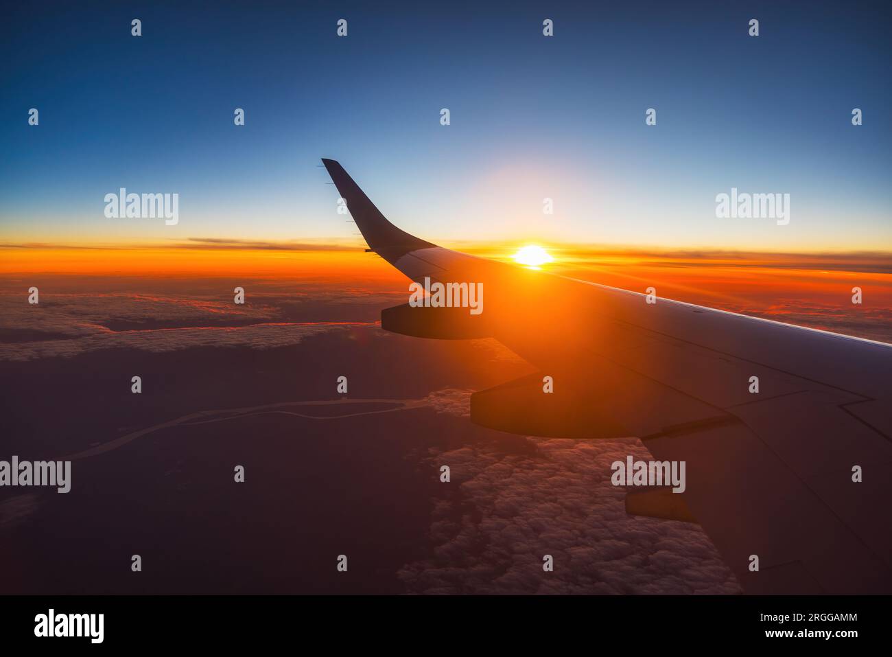 Airplane flight in sunset sky over ocean water and wing of plane. View ...