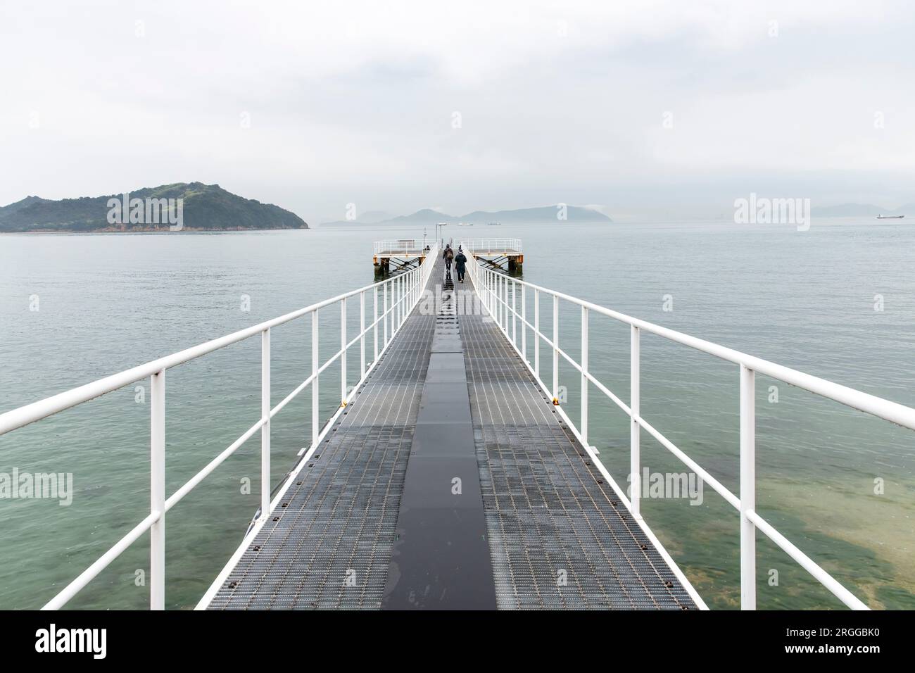 View of two people walking the length of a jetty or pier into the Seto ...