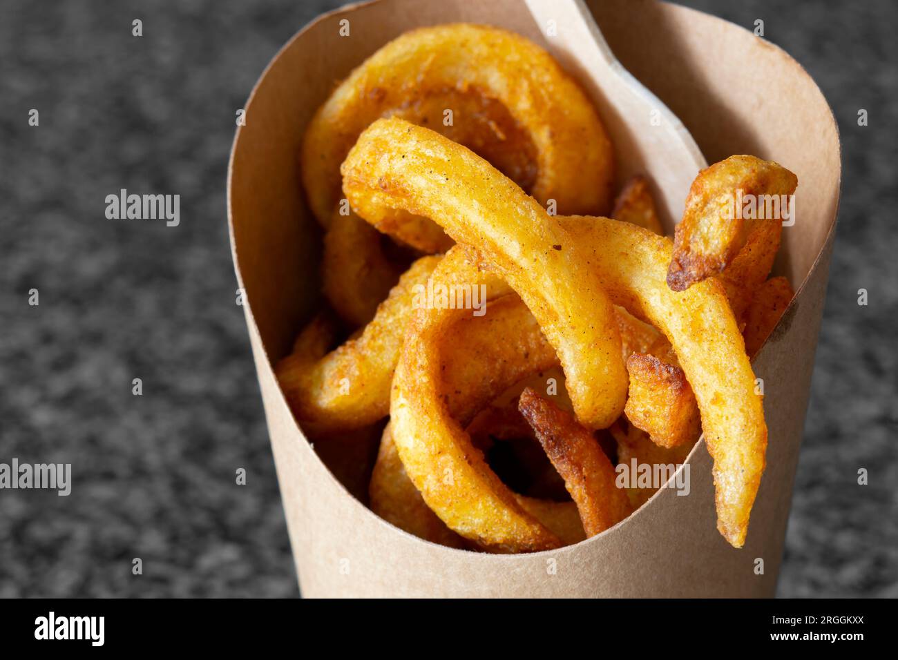 Curly fries takeaway in a cardboard carton with a wooden fork ...