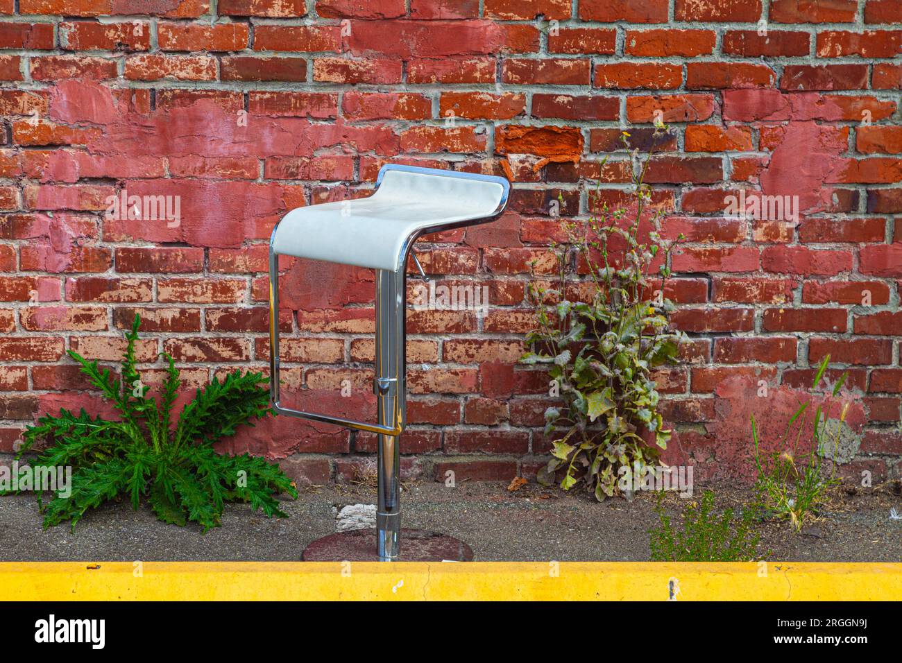Abandoned chrome stool by a weathered red brick wall Stock Photo - Alamy