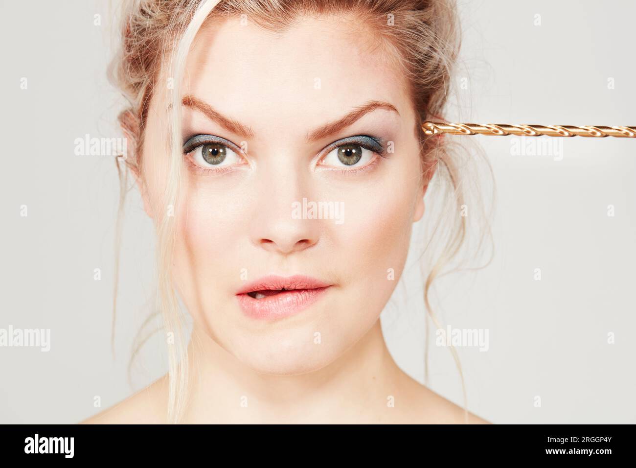 Young woman with drill pressed against her head Stock Photo - Alamy