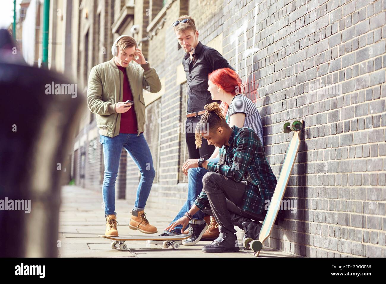Teenage friends leaning on brick wall Stock Photo - Alamy
