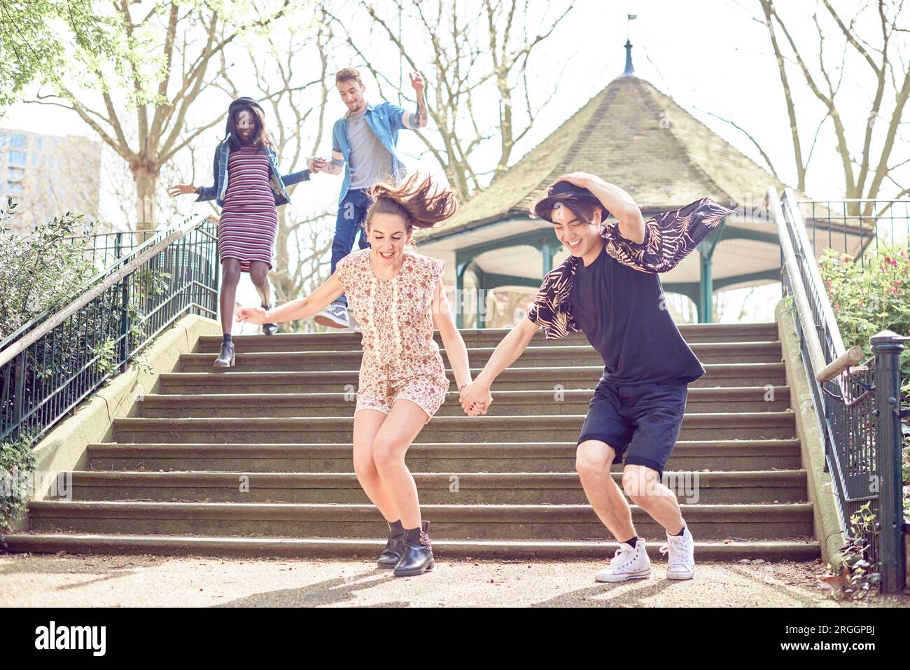 Teenage friends jumping down steps at park Stock Photo - Alamy