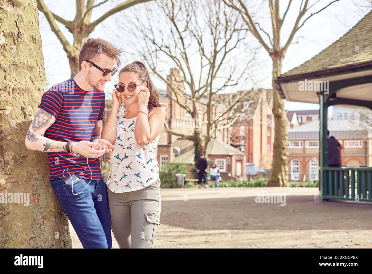 Teenage couple sharing music in park Stock Photo - Alamy