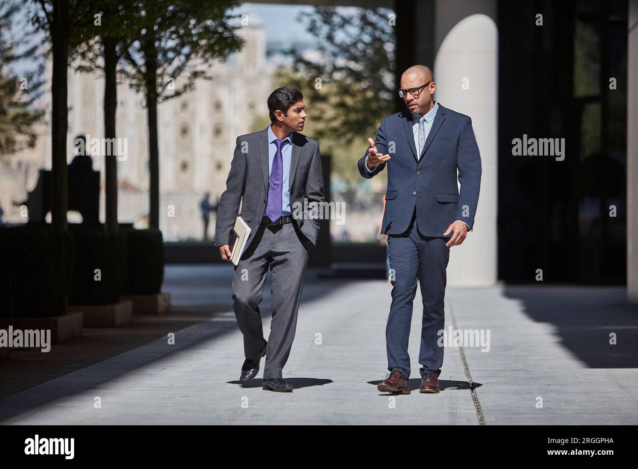 Businessmen walking along sidewalk together Stock Photo - Alamy