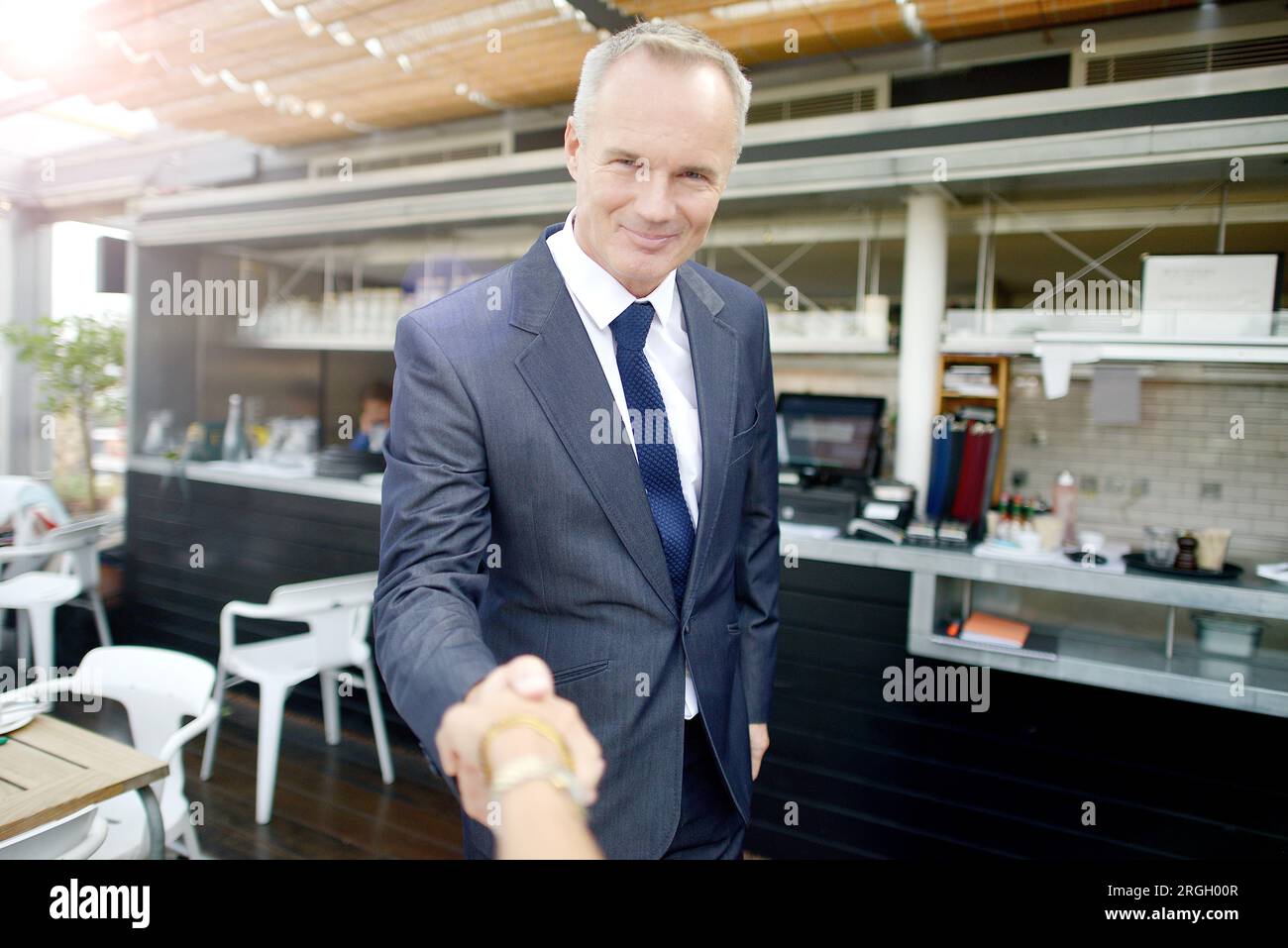 Businessman greeting colleague with handshake at restaurant Stock Photo ...