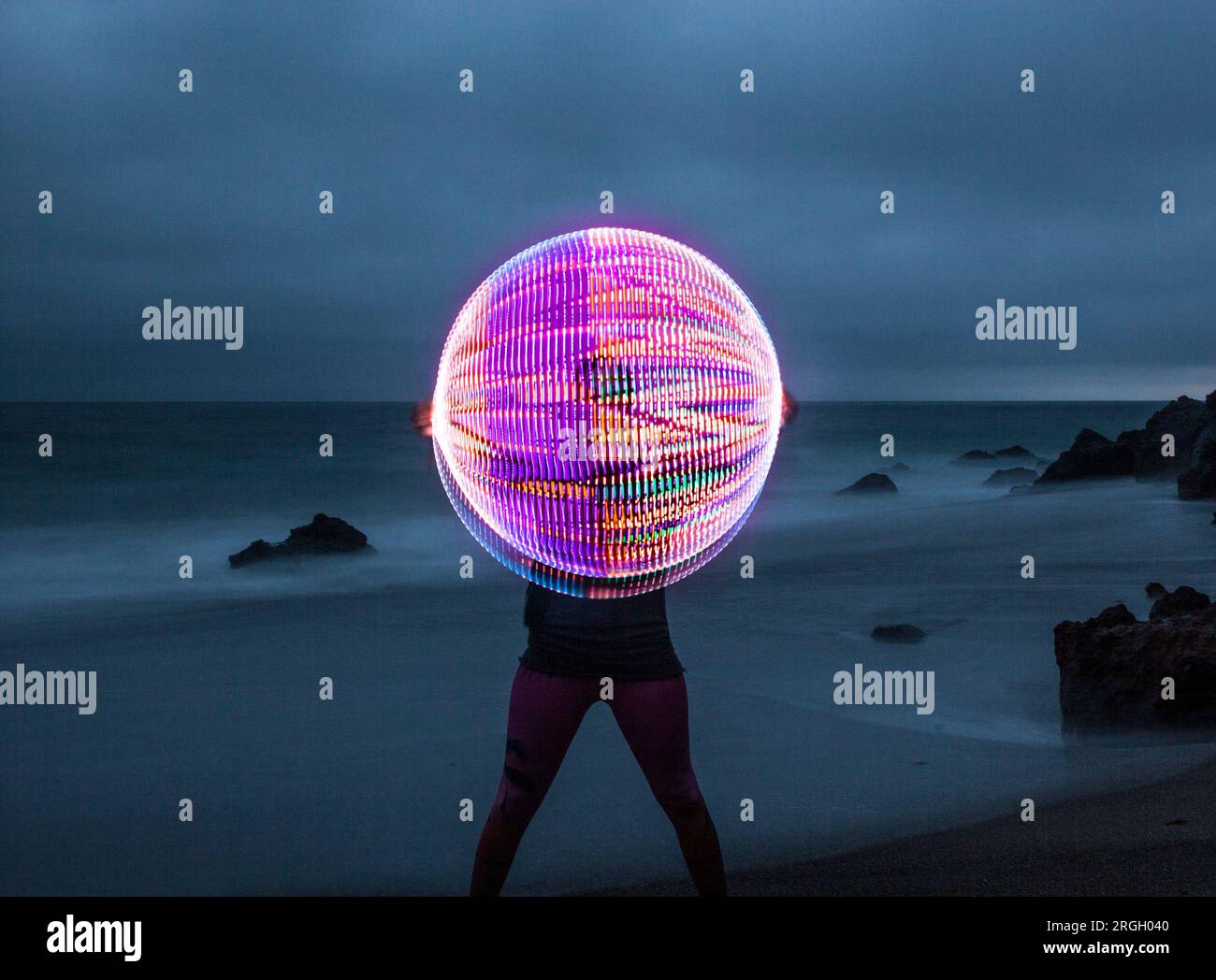 Woman spinning a ball of light on a beach at night Stock Photo - Alamy