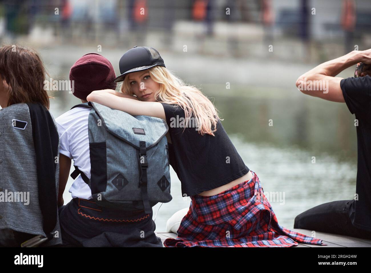 Teenage girl sitting with friends on jetty Stock Photo - Alamy