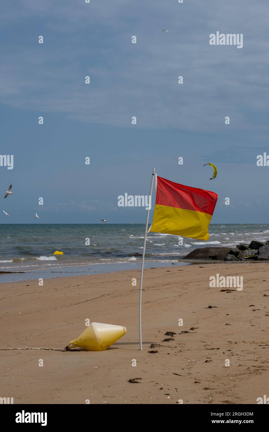 View of the rescue flag, a yellow buoy on the beach and seagulls and ...