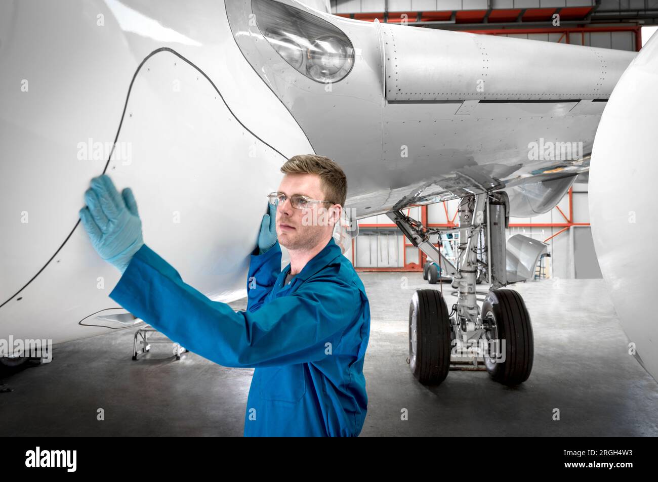 Man working on airplane in hangar Stock Photo - Alamy